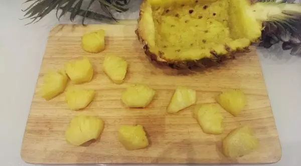 一半的菠萝与雕刻的纸浆和果子片在木切板