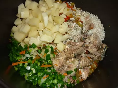 Sirovi krumpir, zeleni luk, sirova riža i konzervirana riba u multikookalnoj zdjeli s prženim povrćem