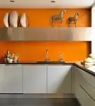 Oransje vegg på kjøkkenet med lette møbler
