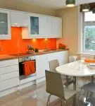 Hvitt hodesett og oransje vegg i kjøkkenet
