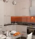Oransje forkle og lyse møbler på kjøkkenet