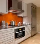Oransje forkle i et lite kjøkken
