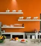 Hvite hyller på bakgrunnen av en oransje kjøkkenvegg