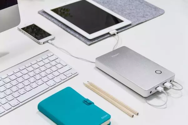Smartphone a tableta ležiace na stole sa nabíjajú z externej batérie