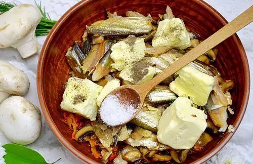 Sayuran panggang, jamur, sprat, mentega dan rempah-rempah dalam nyeri rasa sakit dengan sendok kayu