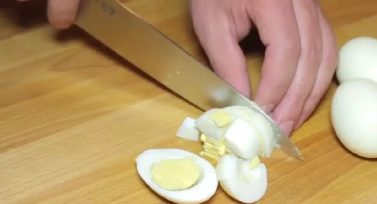 Snijdende gekookte eieren op een houten snijplank