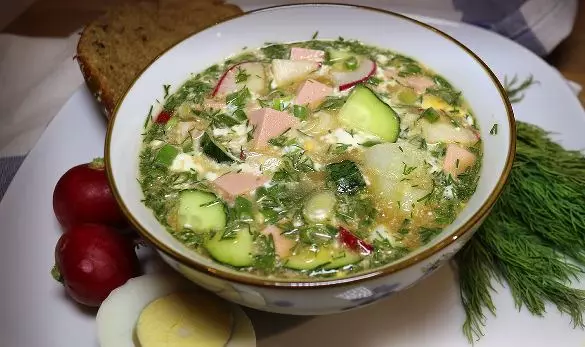 Lente Okroska met zure room en kvass in een diepe plaat op een geserveerde tafel