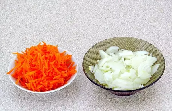 Catturato su una grande grattugia di carote crude e a fette quaterna anelli cipolle in piatti sul tavolo
