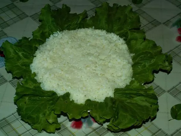 Vařená rýžová vrstva na listech salátu v desce
