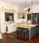 A small island in the kitchen with hanging chandeliers