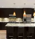 Mörka möbler i ett stort kök med upphängda ljuskronor