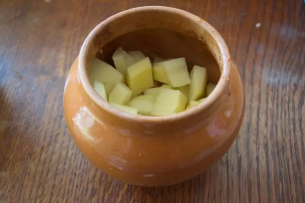 Pommes de terre brute tranchées dans un pot en céramique avec de la viande