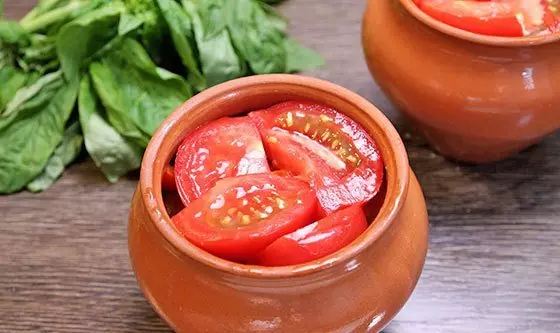 Darnau o domatos aeddfed mewn pot ceramig
