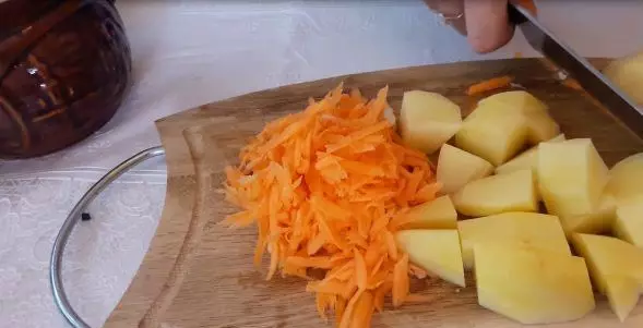 Des pommes de terre brute tranchées et des carottes râpées sur une planche à découper