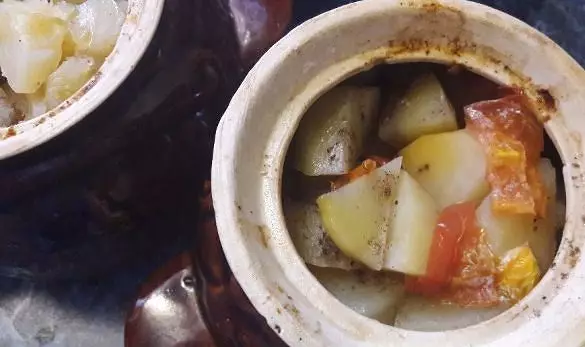 Oală ceramică cu legume de tocană și carne pe masă