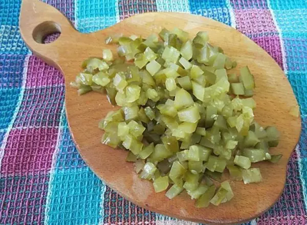 একটি কাঠের কাটিয়া বোর্ডে ছোট কিউব marinated cucumber সঙ্গে কাটা