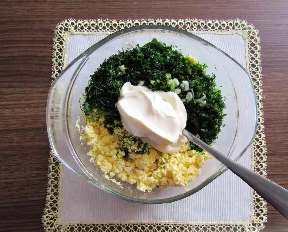 Сјецкани свежи зеленило, дробљена кувана јаја и мајонез у посуди на столу са улптом