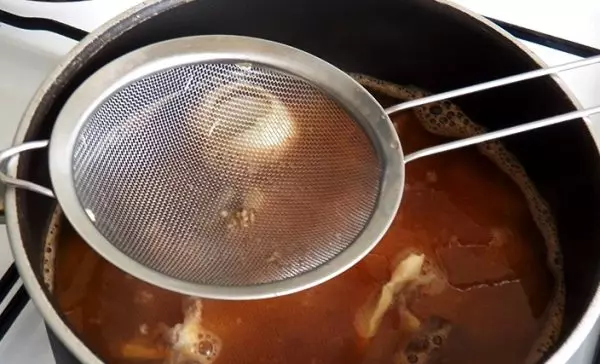 Kleine metalen zeef over pan met soep