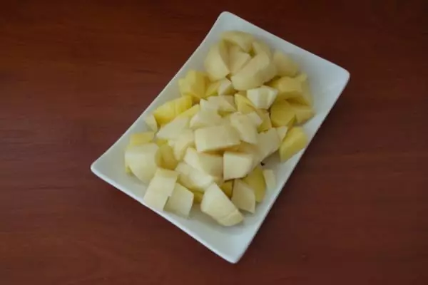 Šķēlēs neapstrādāti kartupeļi uz taisnstūra balta plāksnes