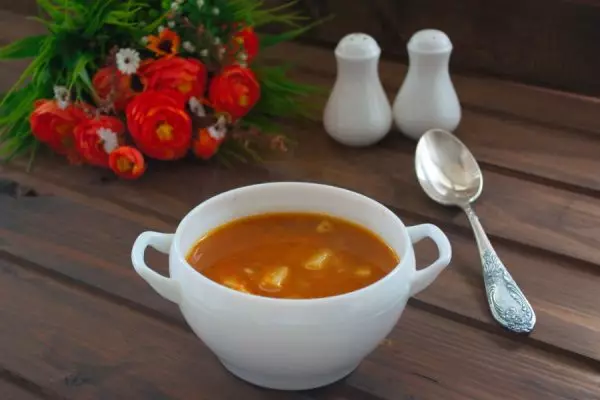 Томато супа со компири, тестенини и пилешко во делови од садови на сервирана маса