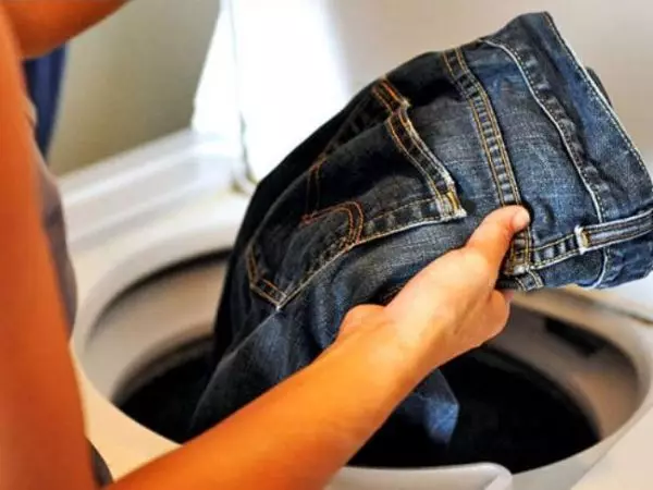 Frau bekommt Jeans von einer Waschmaschine