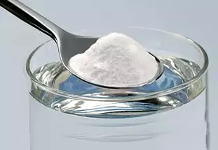 Spoon with dry milk over a glass with water