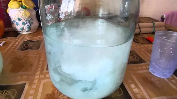 Tiga liter kaleng dengan air di mana susu ditambahkan