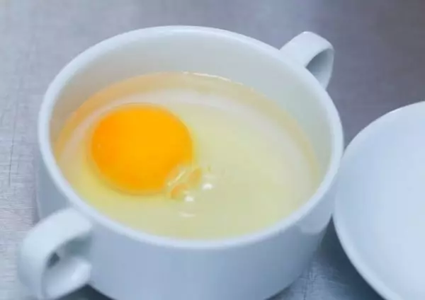 没有壳的未加工的鸡蛋在一个杯子用水
