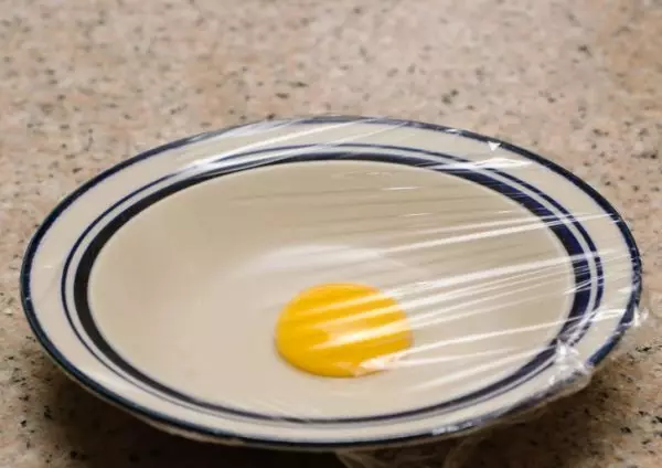 Kuning telur dalam plat di bawah filem makanan