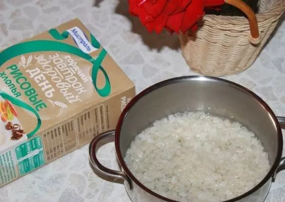 Copos de arroz en una cacerola con agua sobre la mesa.