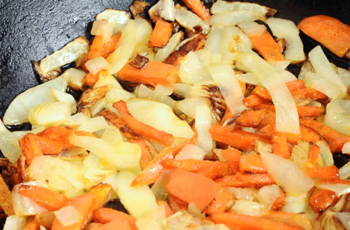 Geroosterde uien en wortelen in een pan