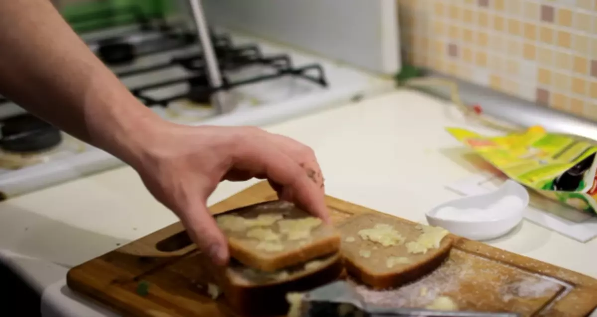 Човек скида горњу кришку хлеба са белим луком