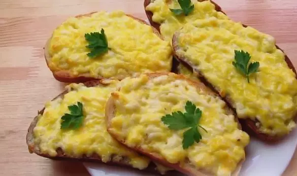 Gatavas karstās sviestmaizes ar kausētu sieru un svaigiem zaļumiem uz balta plāksnes
