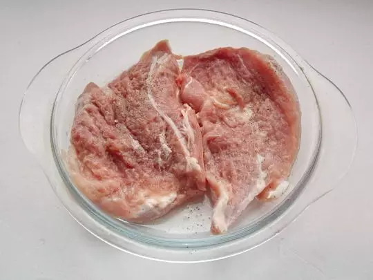 Шматочки свинячої м'якоті в скляній формі для випікання