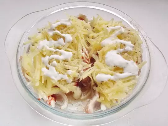 Vlees onder een laag ruwwaardige aardappelen met zure room in glasvorm