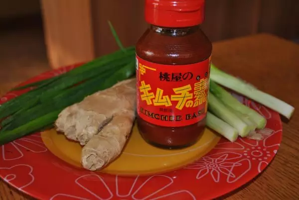 Kimchi kastike, inkivääri ja vihreät sipulit pöydällä