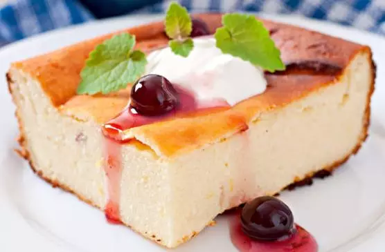 A piece of cottage cheese casserole with jam, natural yoghurt and mint leaves on a plate