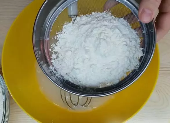Menyaring tepung melalui ayak dalam mangkuk dengan buta