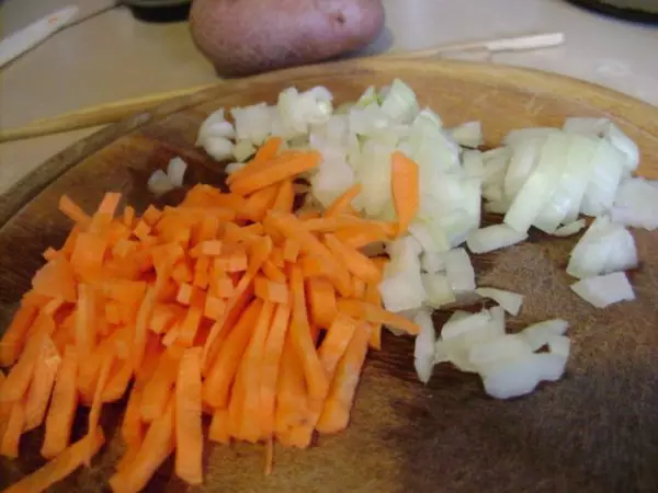Ceapă de măcinare și paie de morcov pe o placă de tăiere
