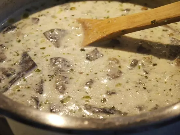 蘑菇湯用牛奶和金屬平底鍋的熔化奶酪