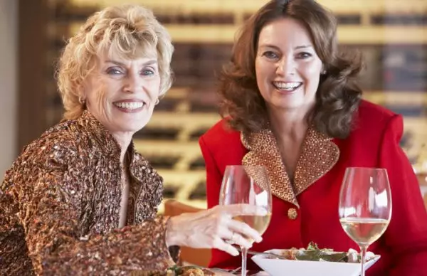 Äldre kvinnor i ett café leende och drick vin