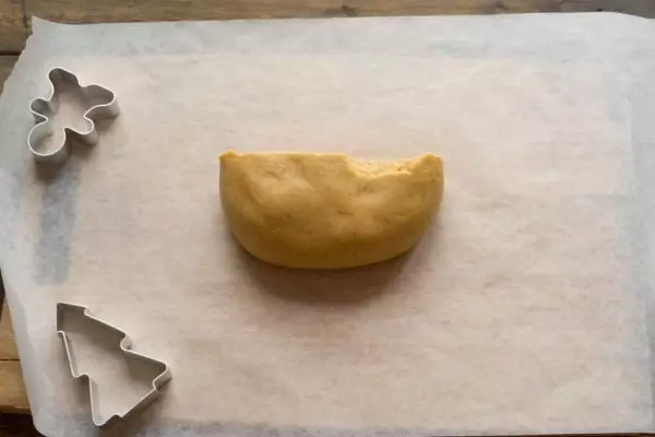 Pedaço de massa e forma de metal para cookies em uma folha de papel de padaria