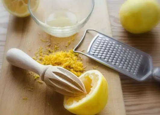 Лимонний сік, цедра, металева терка і ручна соковижималка для цитрусових на столі