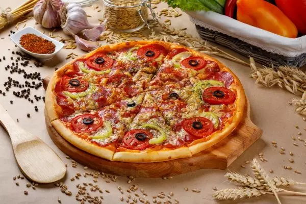 Pizza críochnaithe le ispíní agus ionadaí cáise i bhfoirm meascán de uibheacha agus maonáis
