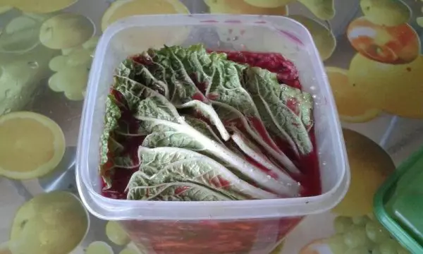 Billet para sa Korean salad sa isang plastic container sa ilalim ng mga sheet ng repolyo