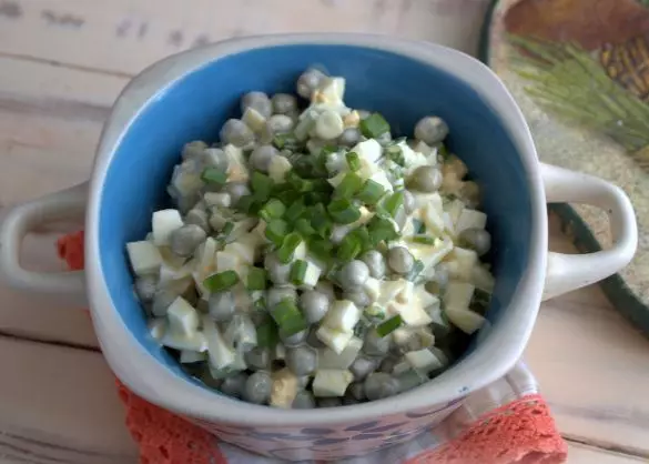 Salad endhog, bawang ijo lan kacang polong sing dikemas nganggo sayuran ijo ing mangkuk salad sing apik ing serbet