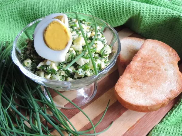 Lukovo-tojás saláta olvasztott sajttal egy vágódeszkán krutonokkal és zöldekkel
