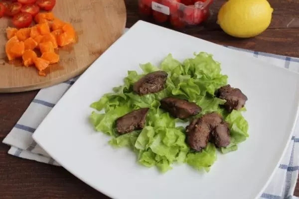 Rostitaj kokidaj hepatoj kaj tranĉaĵoj de salato folioj sur granda telero
