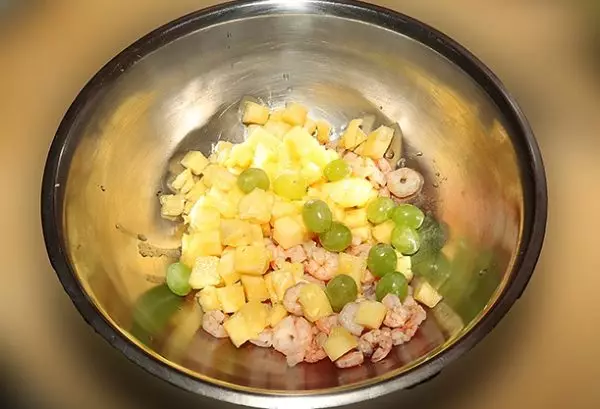Pineapple flesh, shrimp and green grapes in a metal bowl