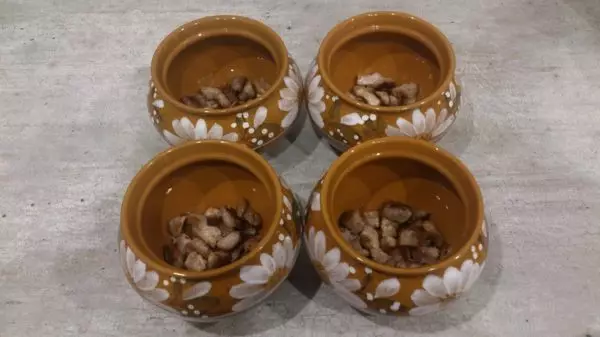 Morceaux de viande rôtie dans des pots en céramique portant